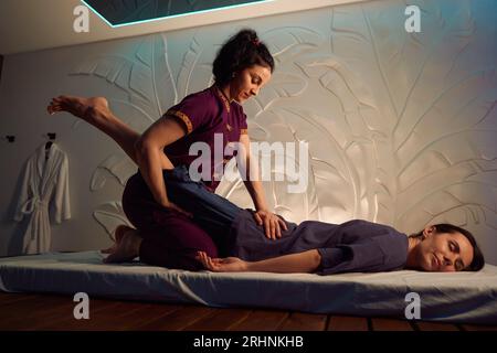 Focused massotherapist stretching female patient psoas muscles Stock ...