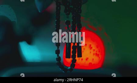 Christian cross on display at car windshield while raining in ...