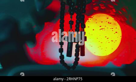 Christian cross on display at car windshield while raining in ...