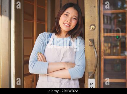 Portrait of asian smiling barista, girl serving coffee, standing near ...