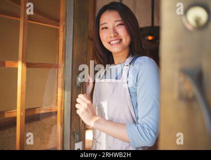 Portrait of asian smiling barista, girl serving coffee, standing near ...