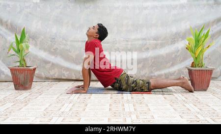Sporty boy doing exercises for flexible spine on studio background ...