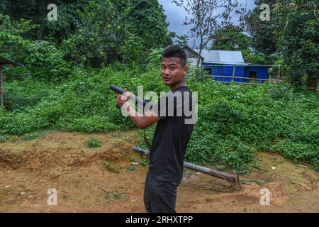 A Kuki volunteer reacts to the camera as he demonstrates a tear gas gun ...