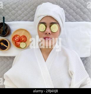 Young Asian woman with cucumber slices relaxing in spa salon Stock ...
