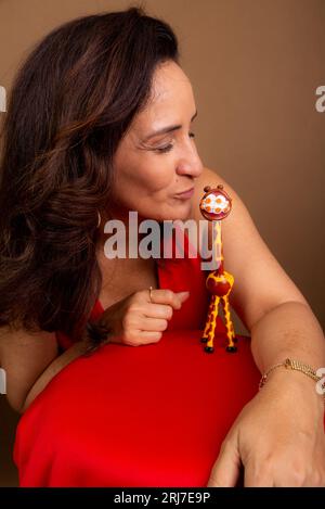 Cheerful coaching woman kissing a giraffe doll. Symbol of non-violent ...