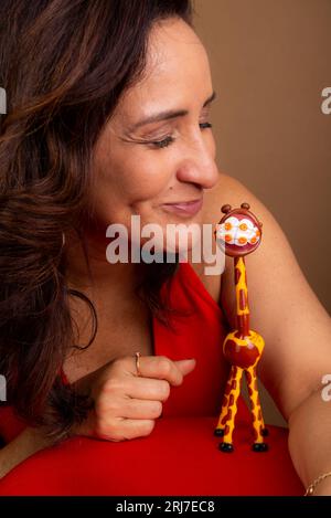Cheerful coaching woman kissing a giraffe doll. Symbol of non-violent ...