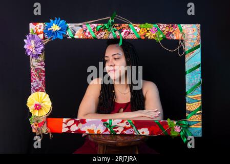 Beautiful woman inside a frame adorned with flowers and colorful cloths ...