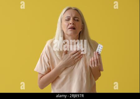 Mature woman with pills having heart attack on white background Stock ...