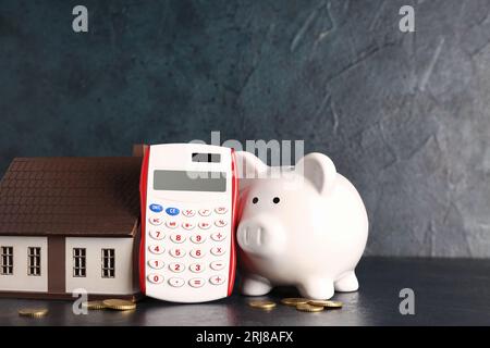 House model with piggy bank and calculator on wooden background ...