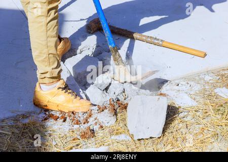 Concrete driveway demolition by worker using pickaxe at construction ...