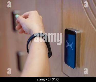 A woman opens the electronic lock of a cubicle in a locker room with a ...