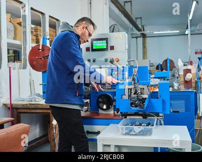 people working in a sticker printing factory. worker uses a stickier ...