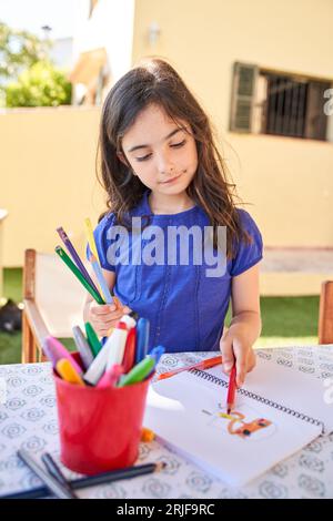Adorable hispanic girl drawing on notebook lying on sofa by christmas ...