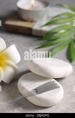 Stones with acupuncture needles and lily flower on grey table, closeup ...
