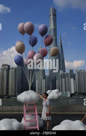 Tourists take photos of a large balloon art installation at the Bund in ...