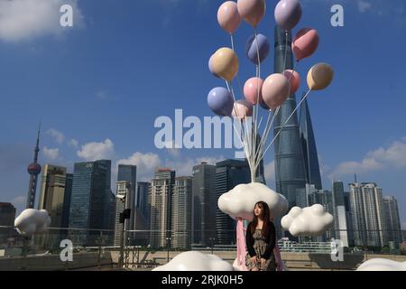 Tourists take photos of a large balloon art installation at the Bund in ...