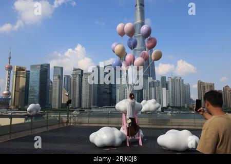 Tourists take photos of a large balloon art installation at the Bund in ...