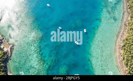 An aerial view of several boats peacefully floating in the pristine ...