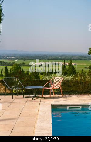 a sun-drenched swimming pool surrounded by lush greenery and empty ...
