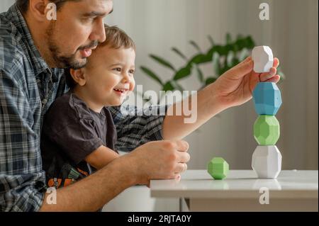 Father and child bonding while building a tower with toy blocks on the ...