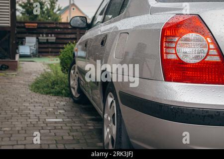 Gray shiny car parked in quiet area on asphalt road on blurred bokeh ...