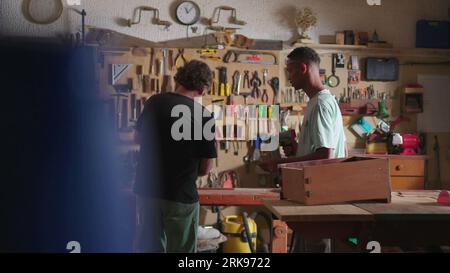 Candid scene of senior carpenter and junior apprentice young man ...