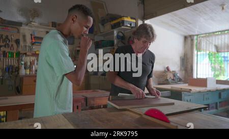 Wood Sawing Scene of Carpenter Guiding Apprentice in Carpentry Workshop ...