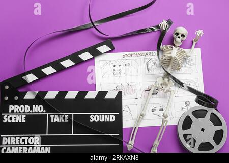 Clapperboard with film reel, storyboard and skeleton on purple ...