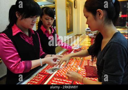 A consumer selects gold jewelry at a store in Huai'an, east China's ...