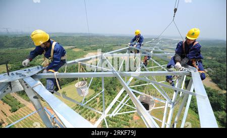 workers next to transmission line tower Stock Photo - Alamy