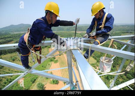 workers next to transmission line tower Stock Photo - Alamy