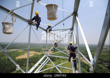 workers next to transmission line tower Stock Photo - Alamy