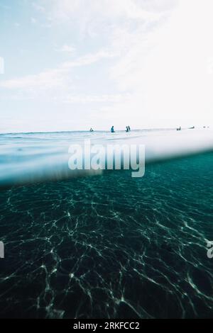 Pulled back view of surfer sitting on surfboard, black and white Stock ...