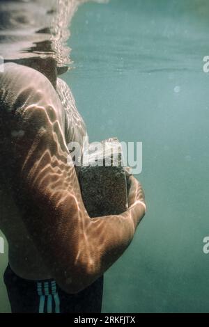A young male holds a cement brick underwater Stock Photo - Alamy