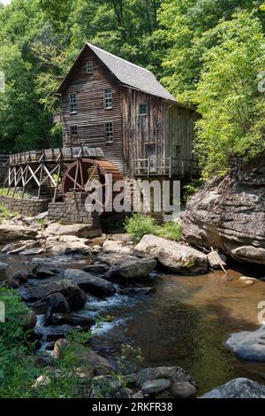 A wooden house with a cascading stream running through a lush green ...