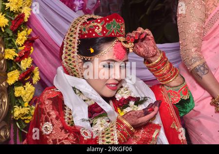 A happy smiling Nepali bride iwearing a red saree and gold jewelry ...