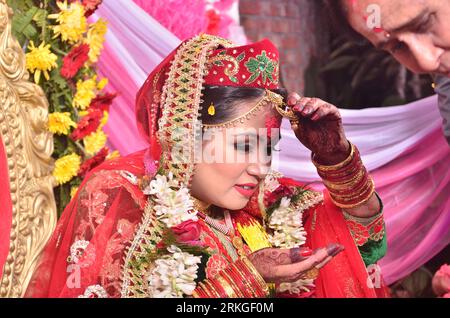 A happy smiling Nepali bride iwearing a red saree and gold jewelry ...