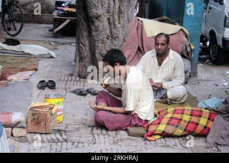 A Pakistani drug addict smokes heroin on a roadside in Karachi ...