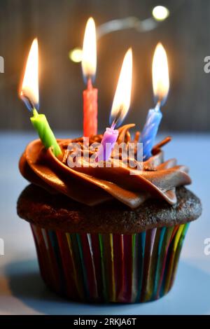 Chocolate cupcake with four colorful lit birthday candles Stock Photo ...
