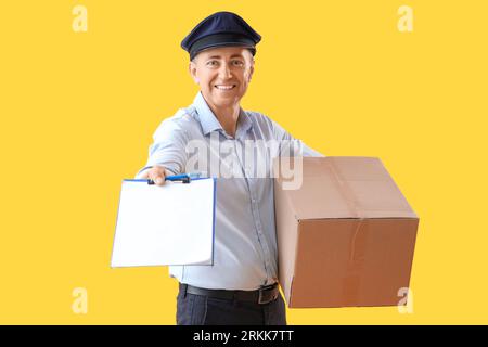 Mature postman with clipboard and parcel on yellow background Stock ...