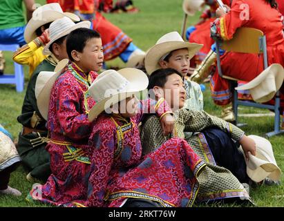 Young Mongolian boys dressed in traditional clothes enjoy a family ...