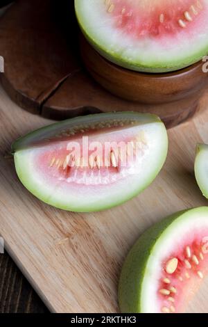 Cut an unripe small watermelon on the table, cut a red and white unripe ...