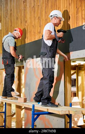 Construction workers install wooden beams panels on new porch in forest ...