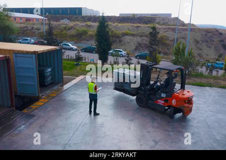 Forklift puts cargo from warehouse to truck. forklift operating outside ...