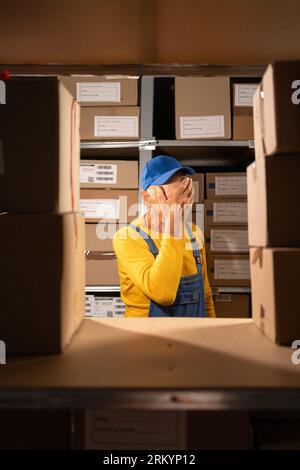 Tired, exhausted warehouse elderly worker has problems with inventory ...