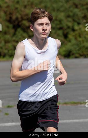Fit and sporty teenage boy running during a warm summer’s afternoon ...