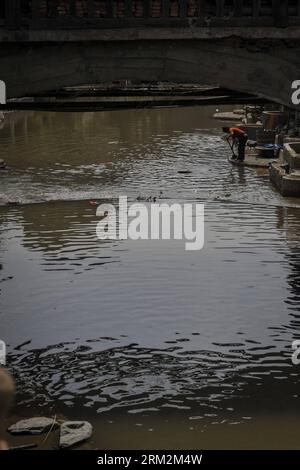 A Dong woman washes her clothes in the village of Zhaoxing. Over her ...
