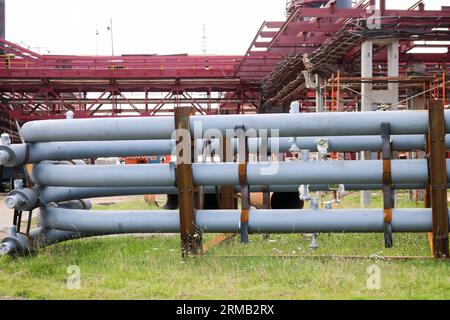 A large iron metal piping trestle with pipes and electric wires and ...