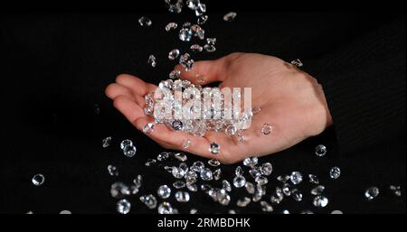 Diamonds falling into Hand against Black Background Stock Photo - Alamy
