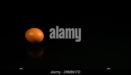 Egg falling and Exploding on black background Stock Photo - Alamy